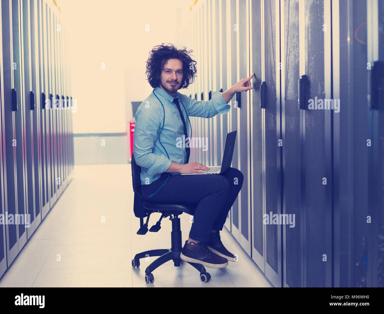 Male IT engineer working on a laptop in server room at modern data ...