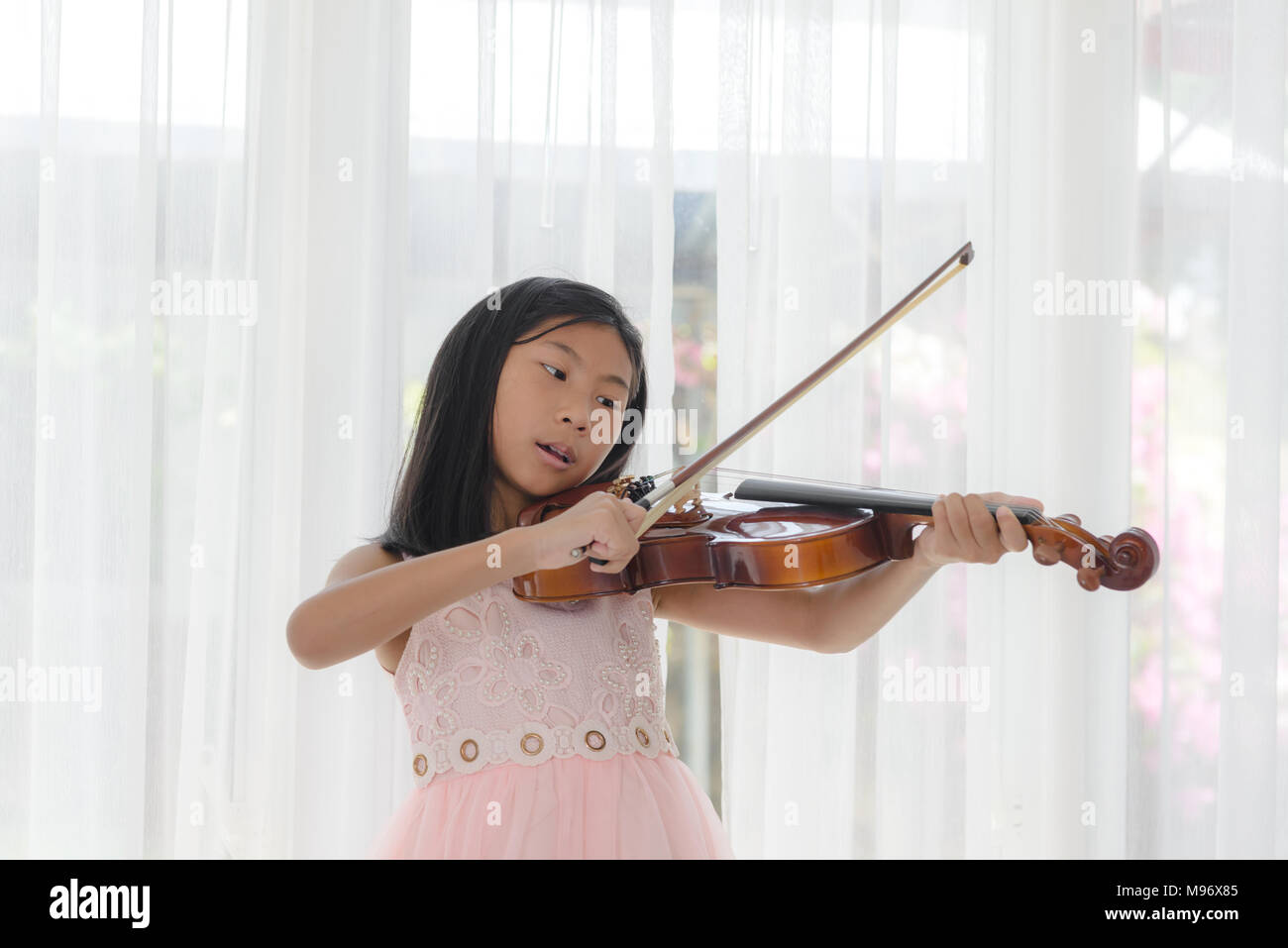 Cute girl playing violin near window at home Stock Photo - Alamy