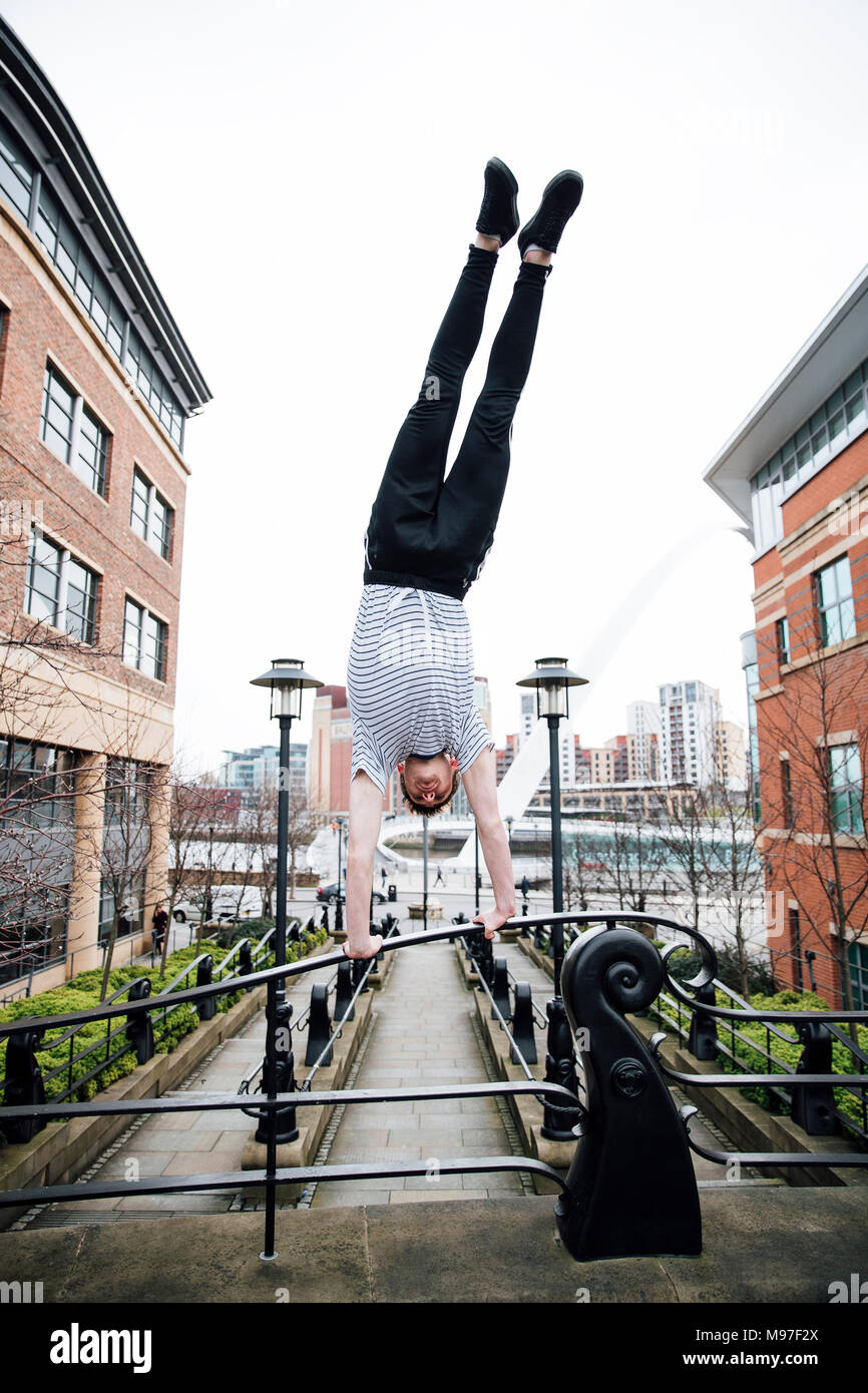 Teenage freerunner is doing a handstand on bridge railings in the city ...
