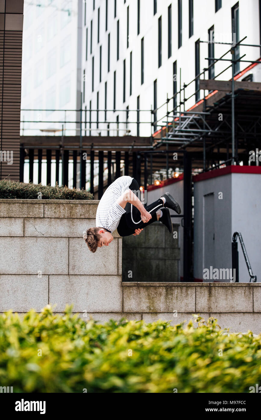 Freerunner is doing a flip from a wall in the city Stock Photo - Alamy