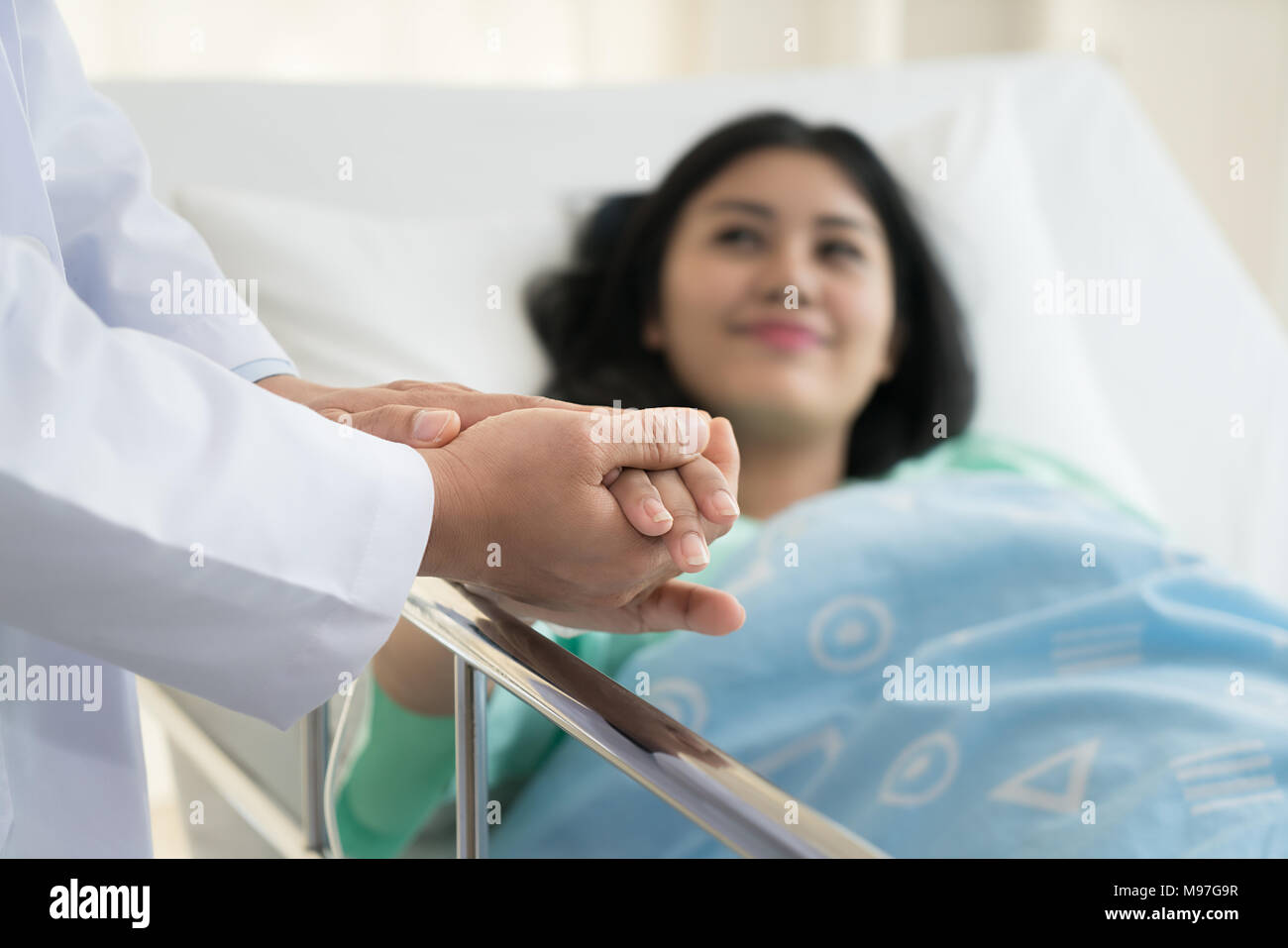 Friendly man doctor hands holding patient hand sitting at the desk for ...