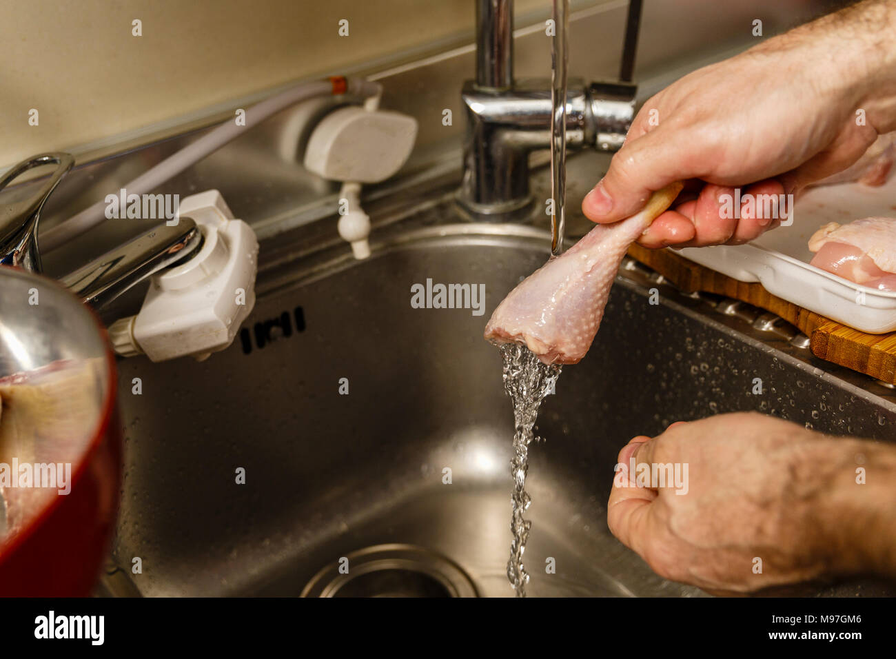 Man washing chicken drumsticks under tap water in the kitchen Stock ...