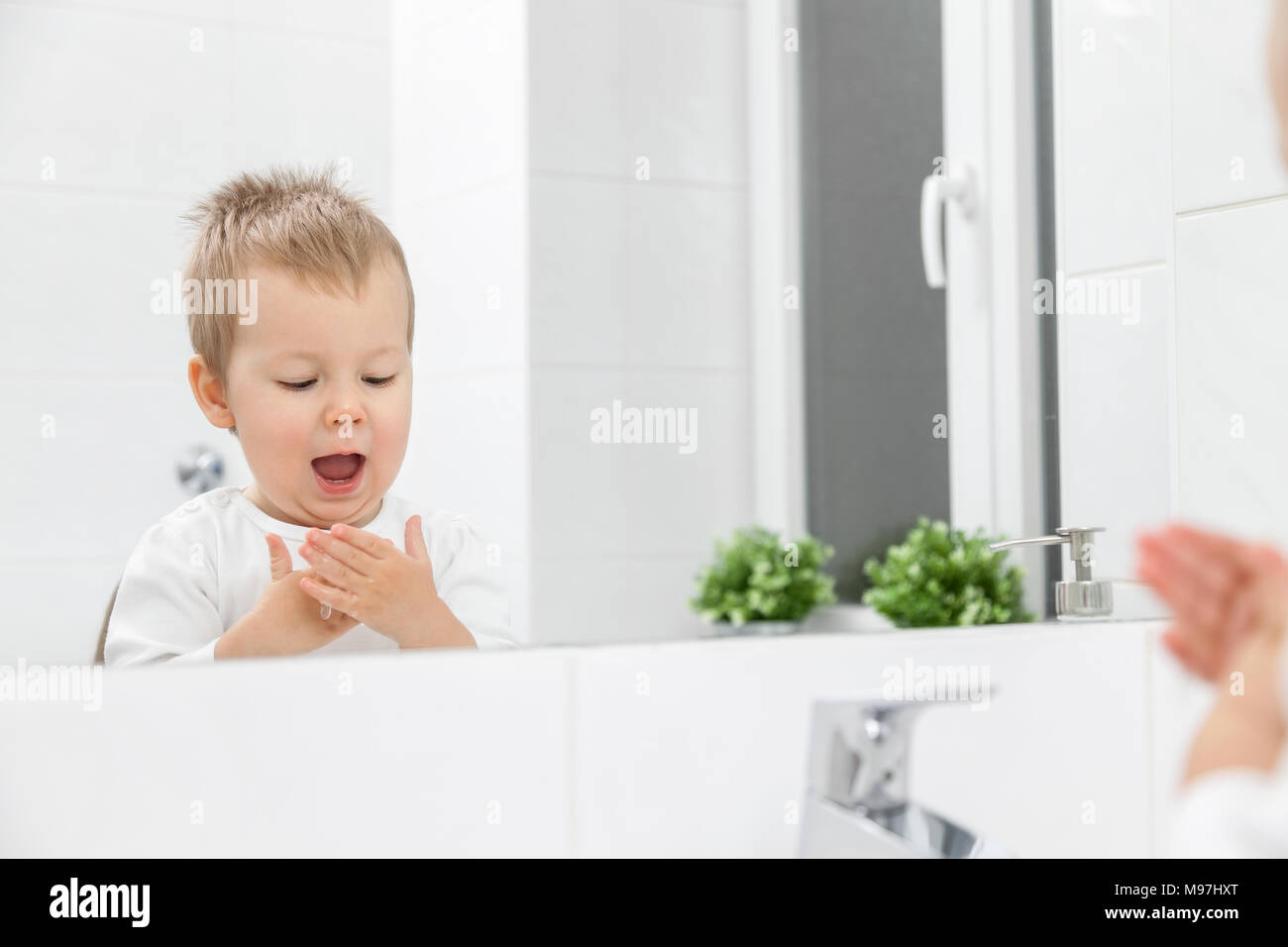 Cute toddler in the bathroom mirror learning how to wash his face Stock ...