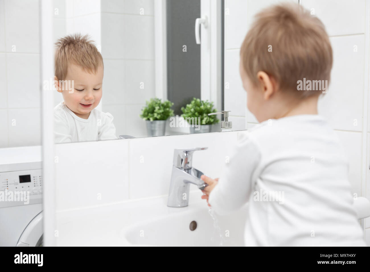 Cute toddler in the bathroom mirror learning how to wash his face Stock ...