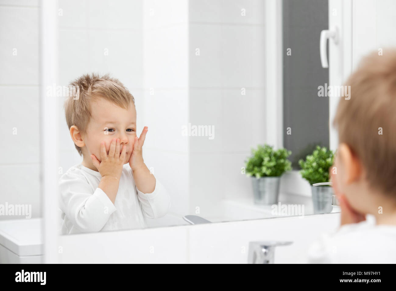 Cute toddler in the bathroom mirror learning how to wash his face Stock ...