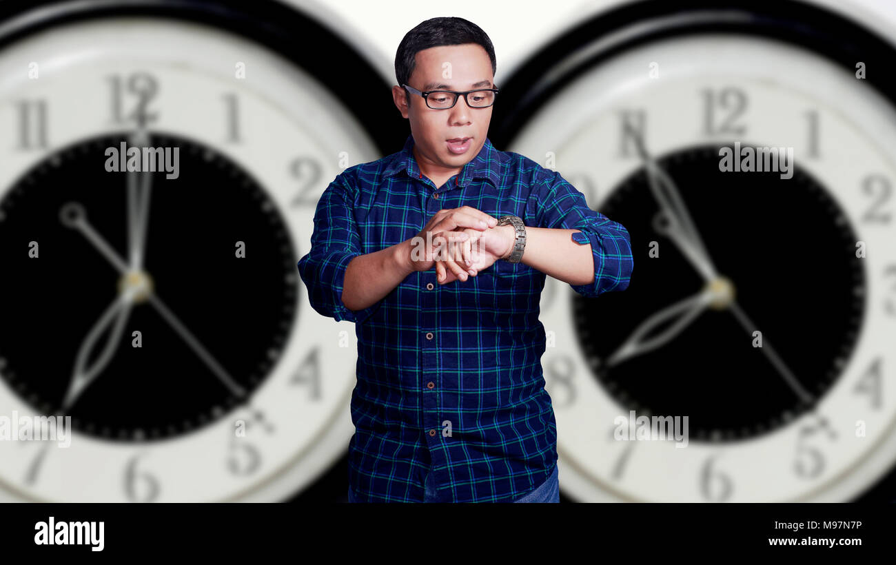 Portrait of a asian young man late for work concept with clock ...