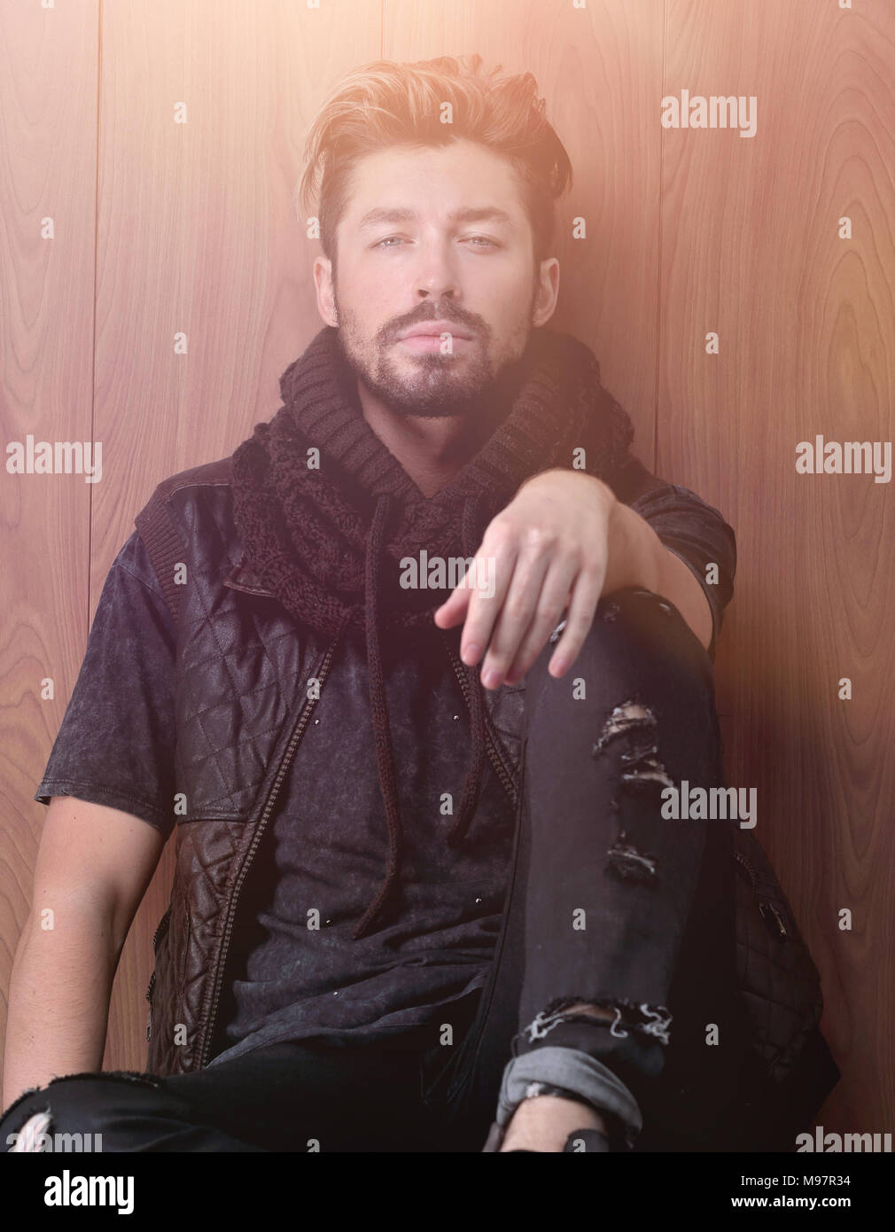 Vogue shot of a beautiful male model in jeans and a vest sitting on a ...