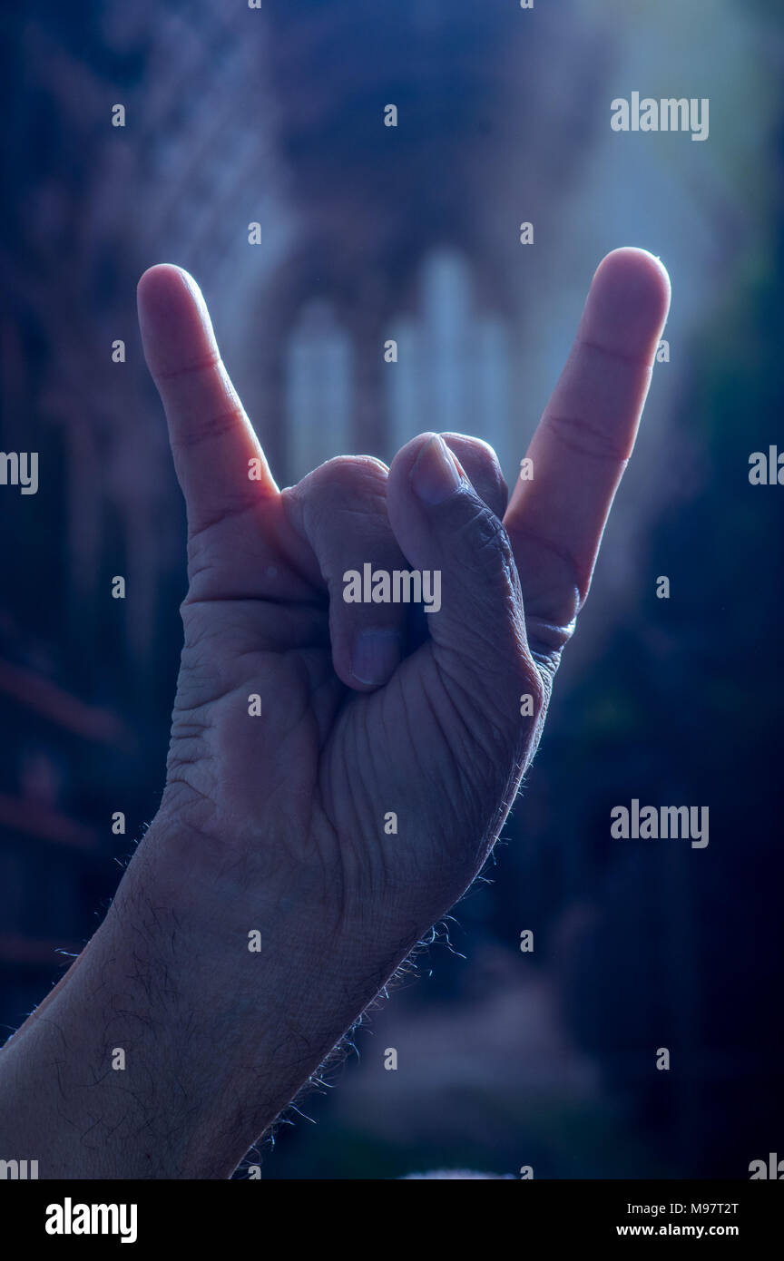 Close up of hand doing a horn sign at dark background Stock Photo - Alamy