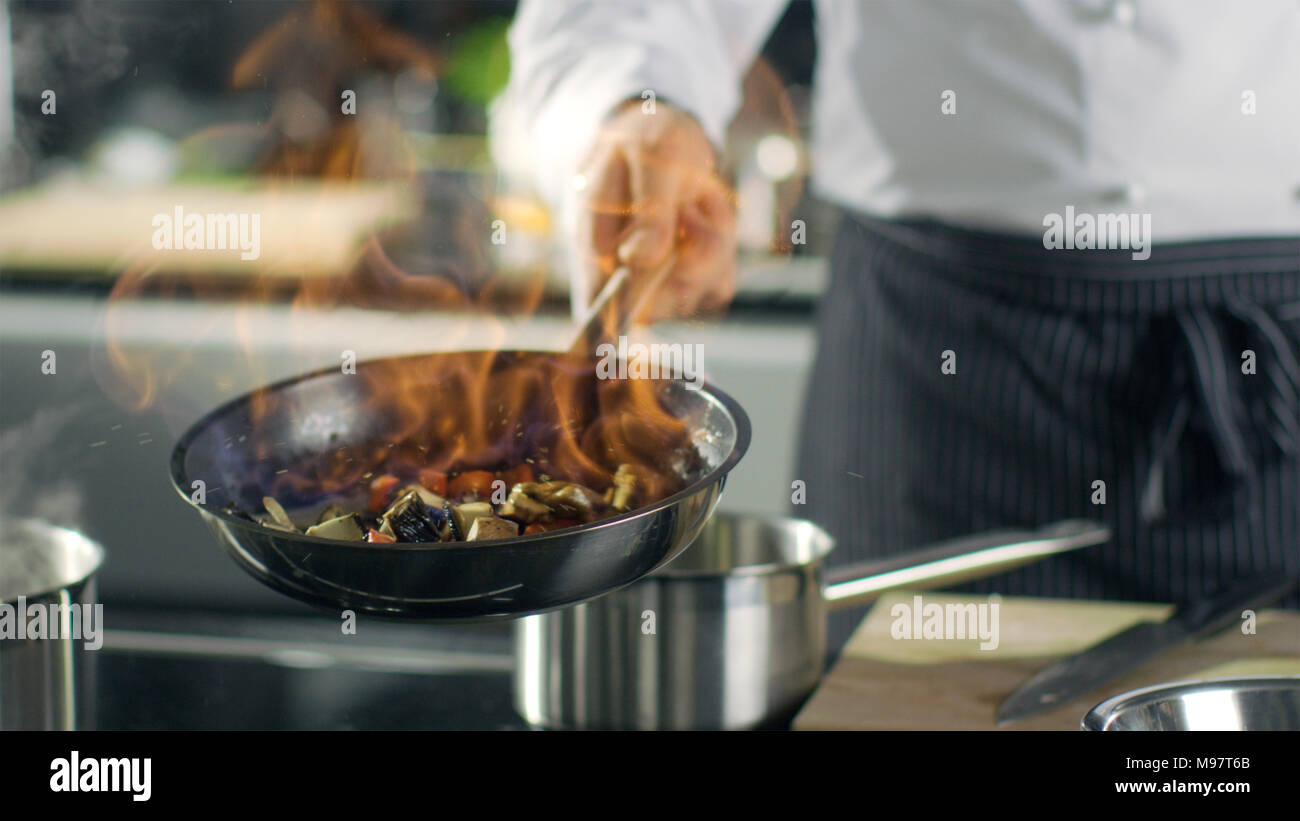 Professional Chef Cooks Flambe Style. He Prepares Dish in a Pan with ...