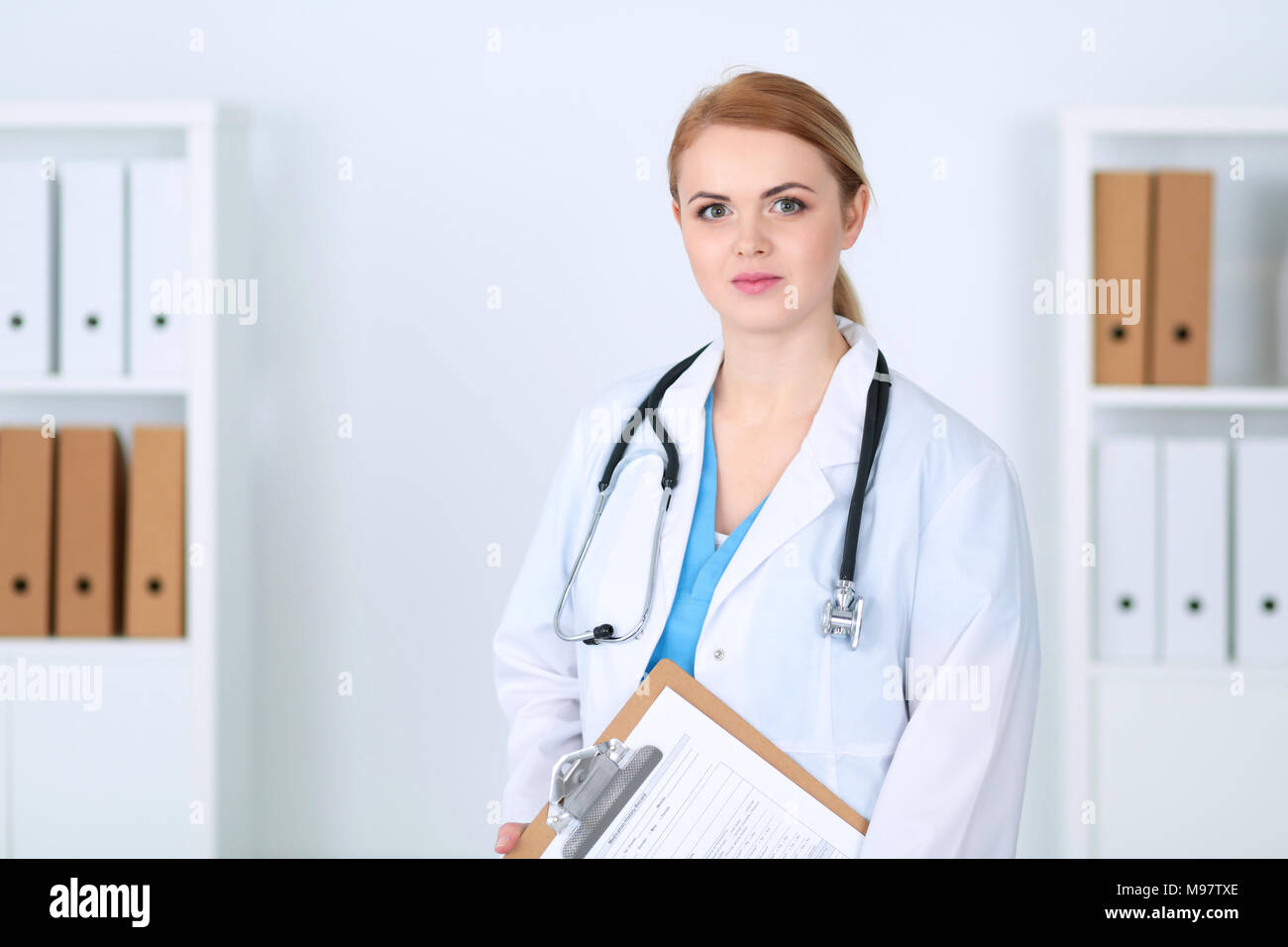 Beautiful female medical doctor standing at hospital. Physician is ...