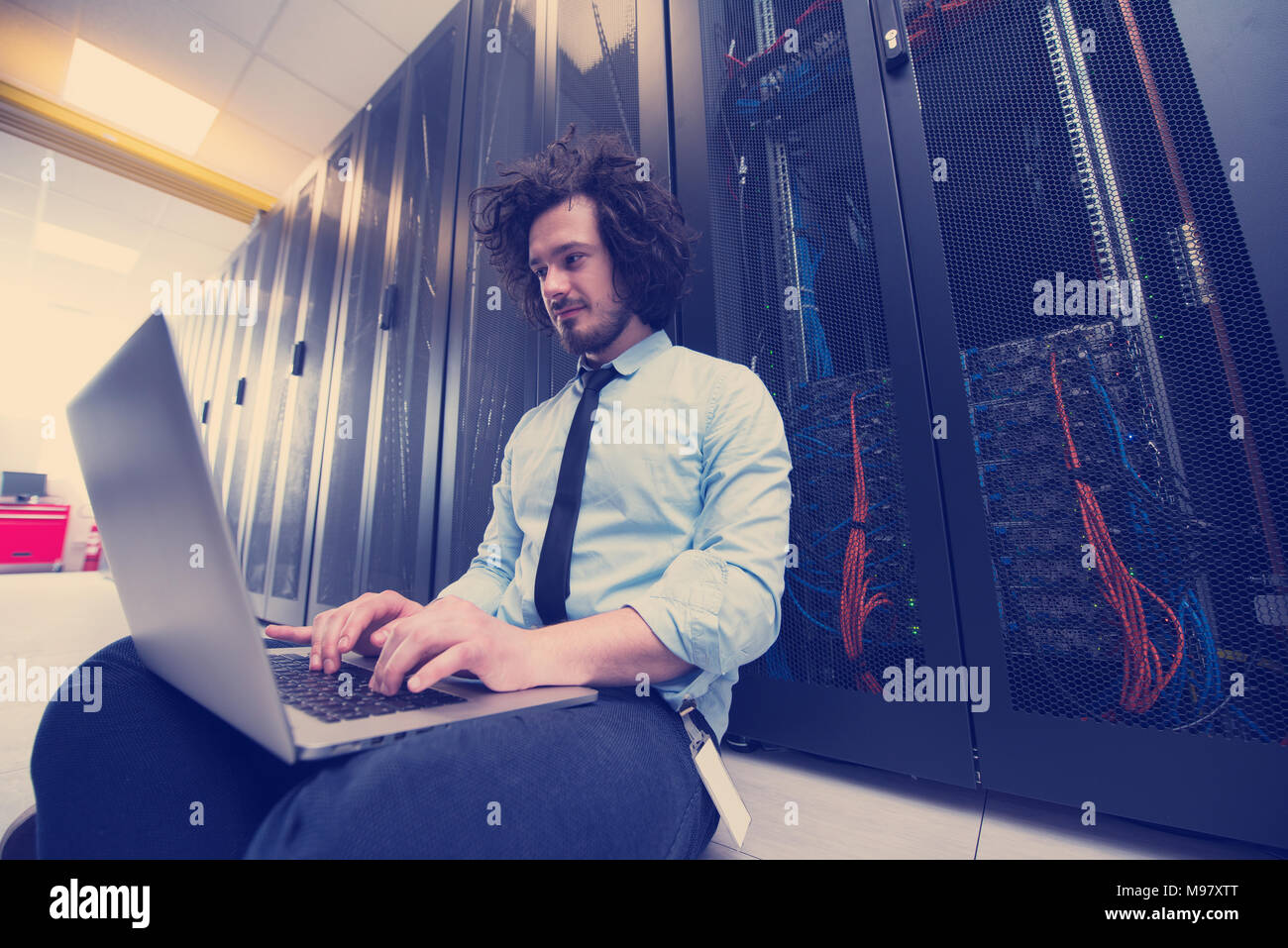 Male IT engineer working on a laptop in server room at modern data ...