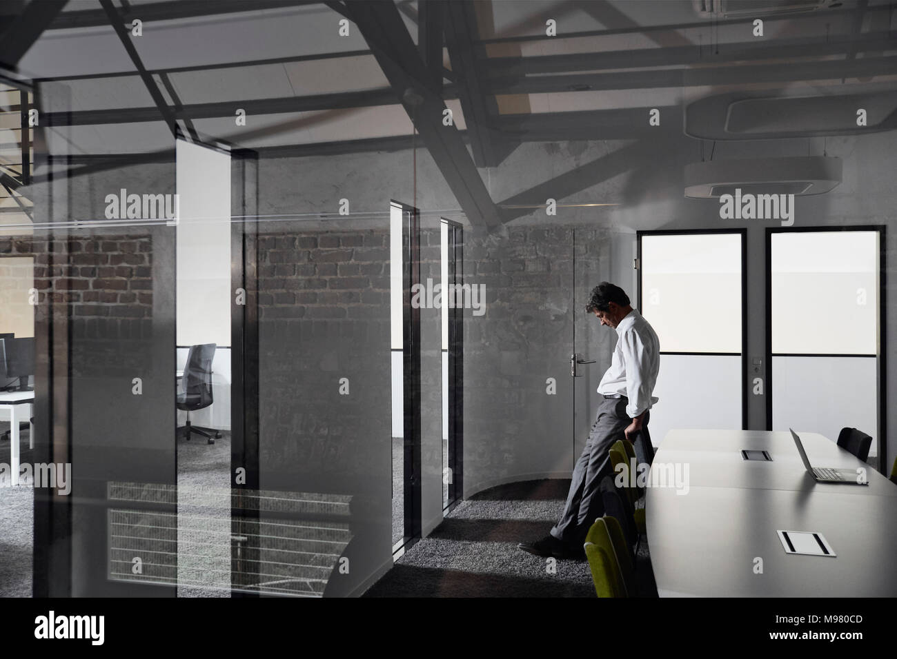 Exhausted and frustrated businessman standing in modern conference room ...