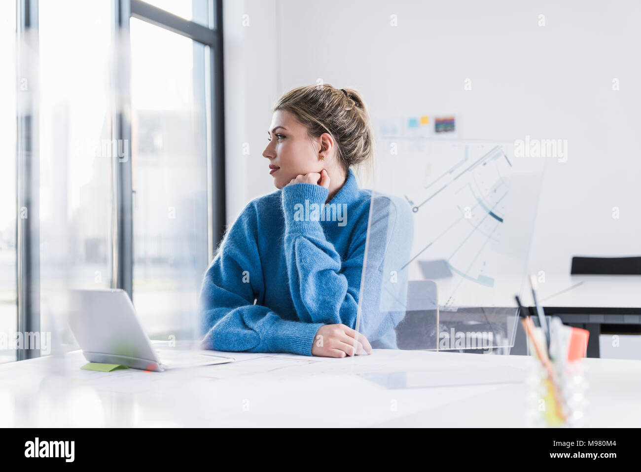 Young woman with laptop and transparent design at desk in office ...