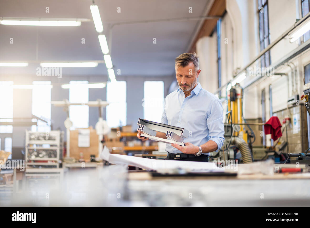 Mature businessman in factory examining component Stock Photo - Alamy