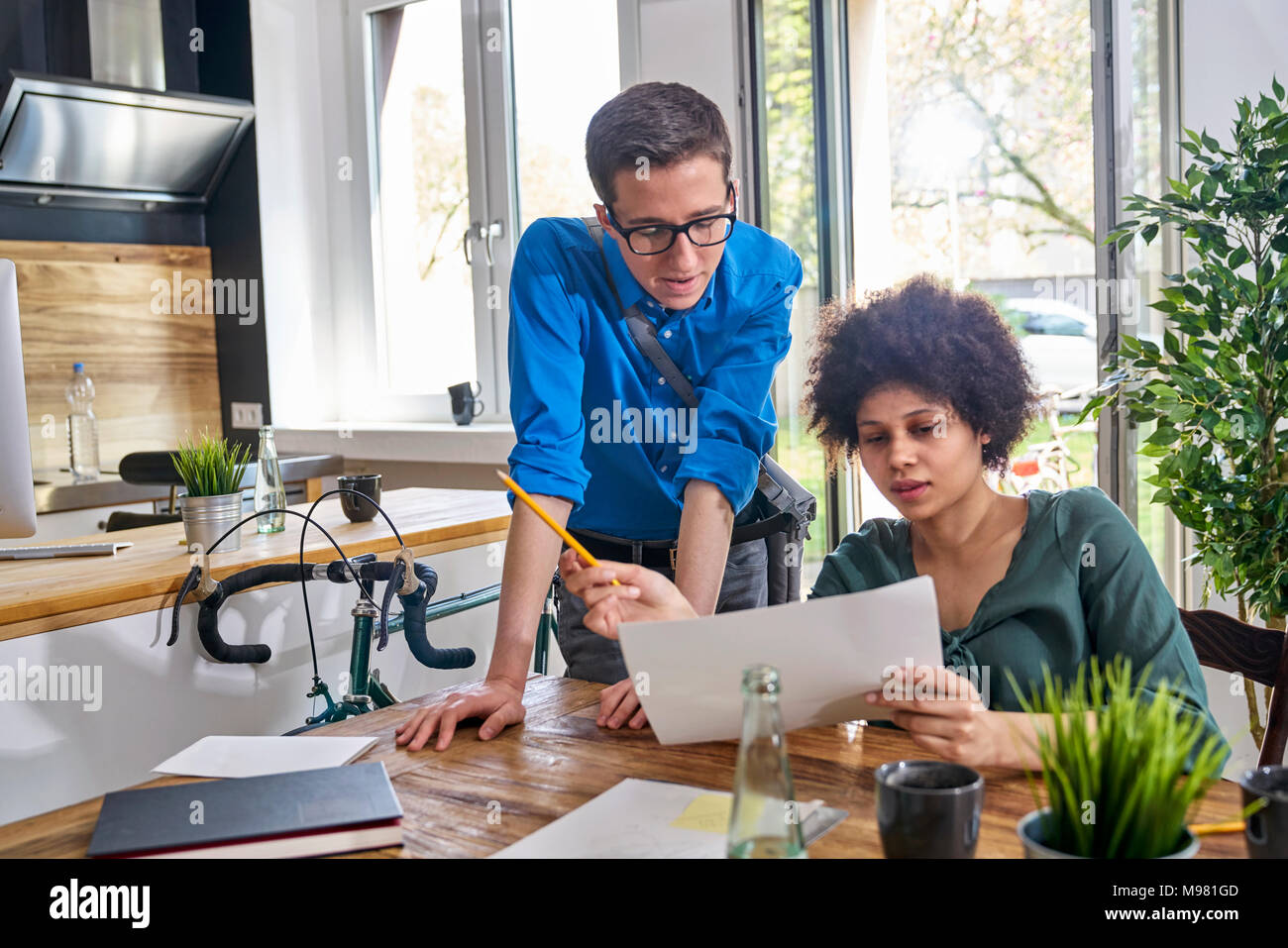 Two colleagues discussing paper in modern office Stock Photo - Alamy