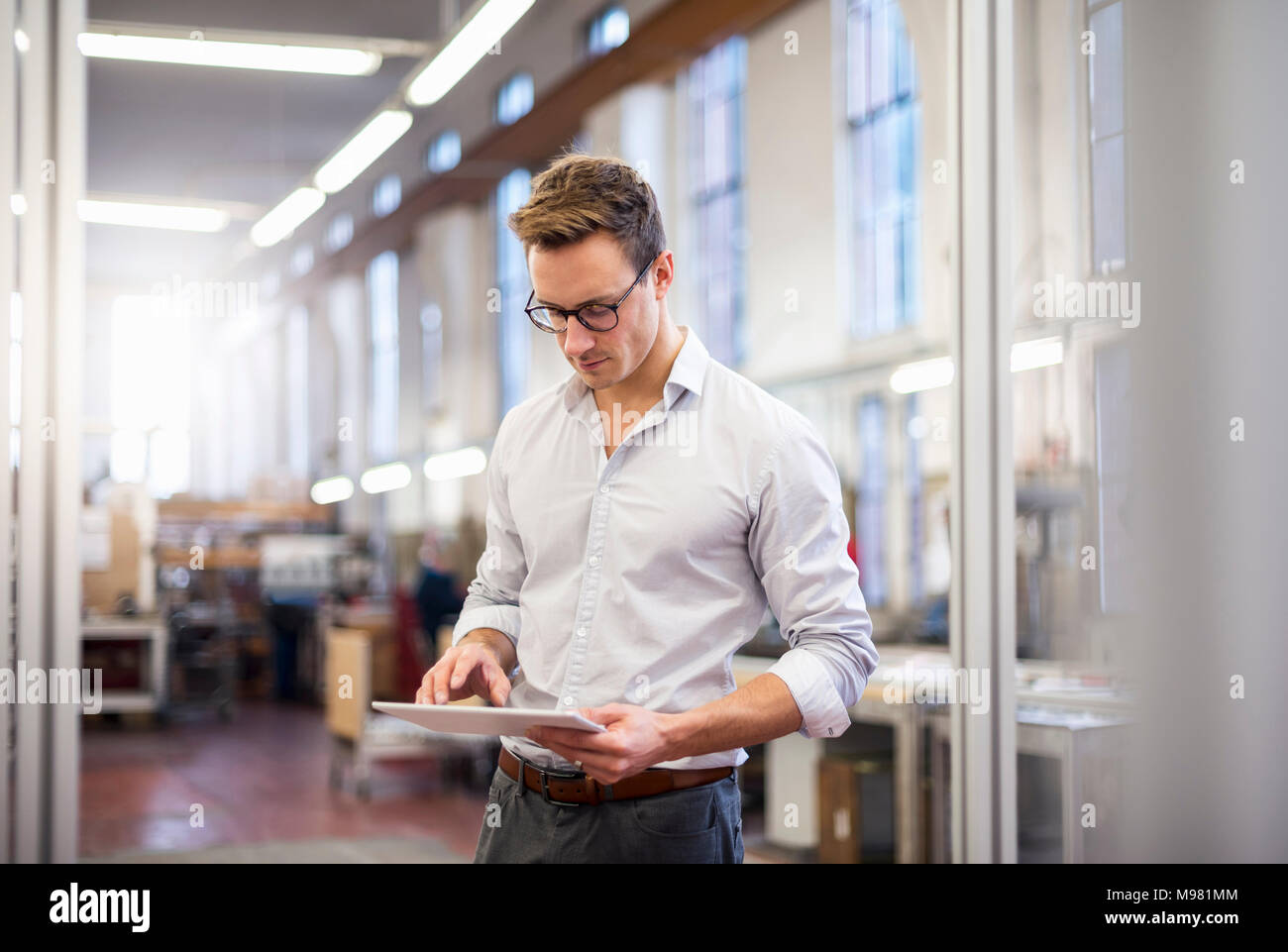 Young businessman in factory using tablet Stock Photo - Alamy
