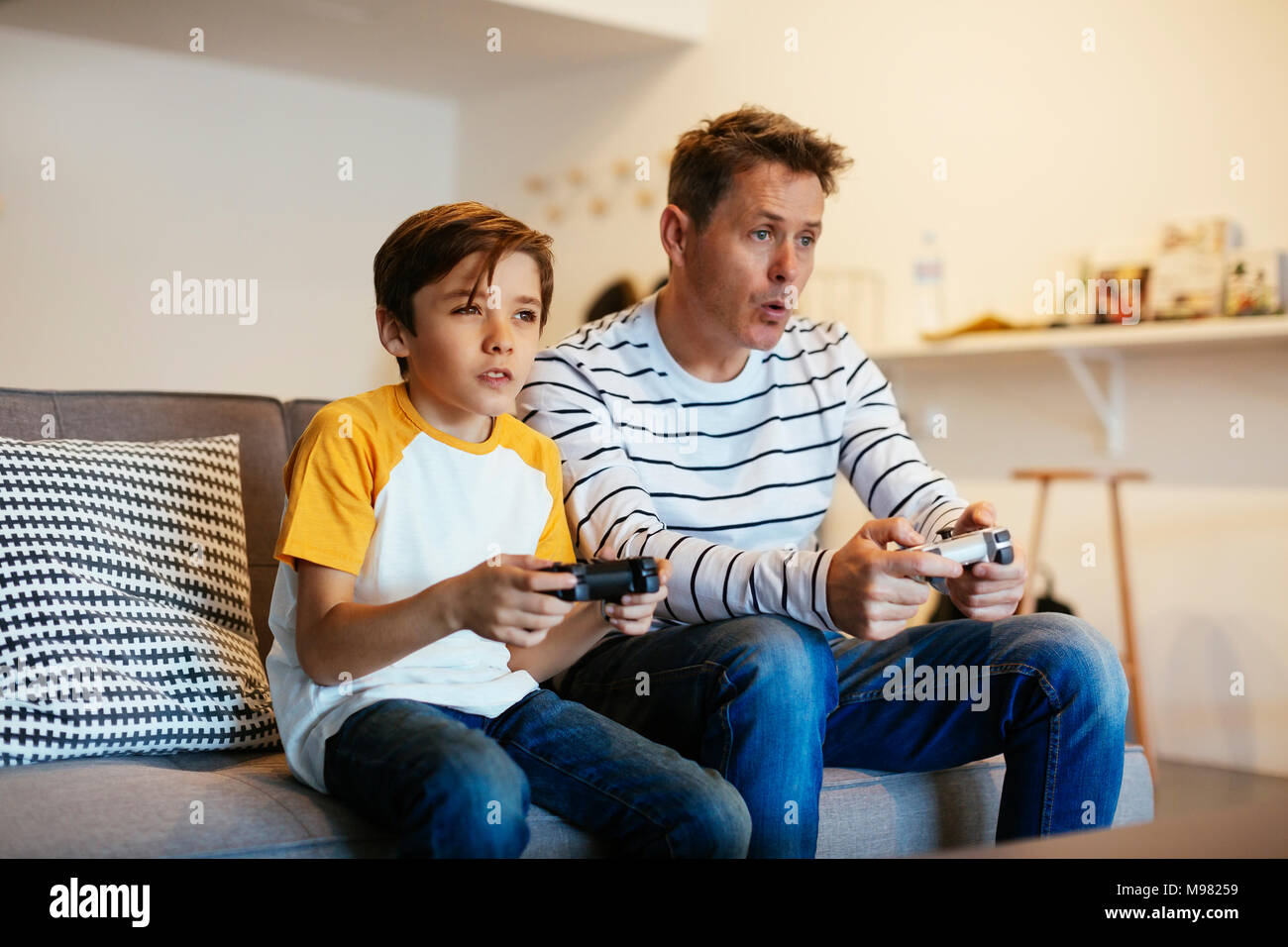 Father and son playing video game on couch at home Stock Photo - Alamy