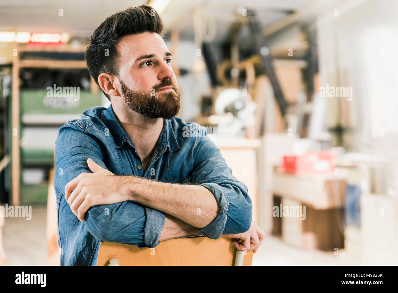 Man sitting on chair in workshop Stock Photo - Alamy