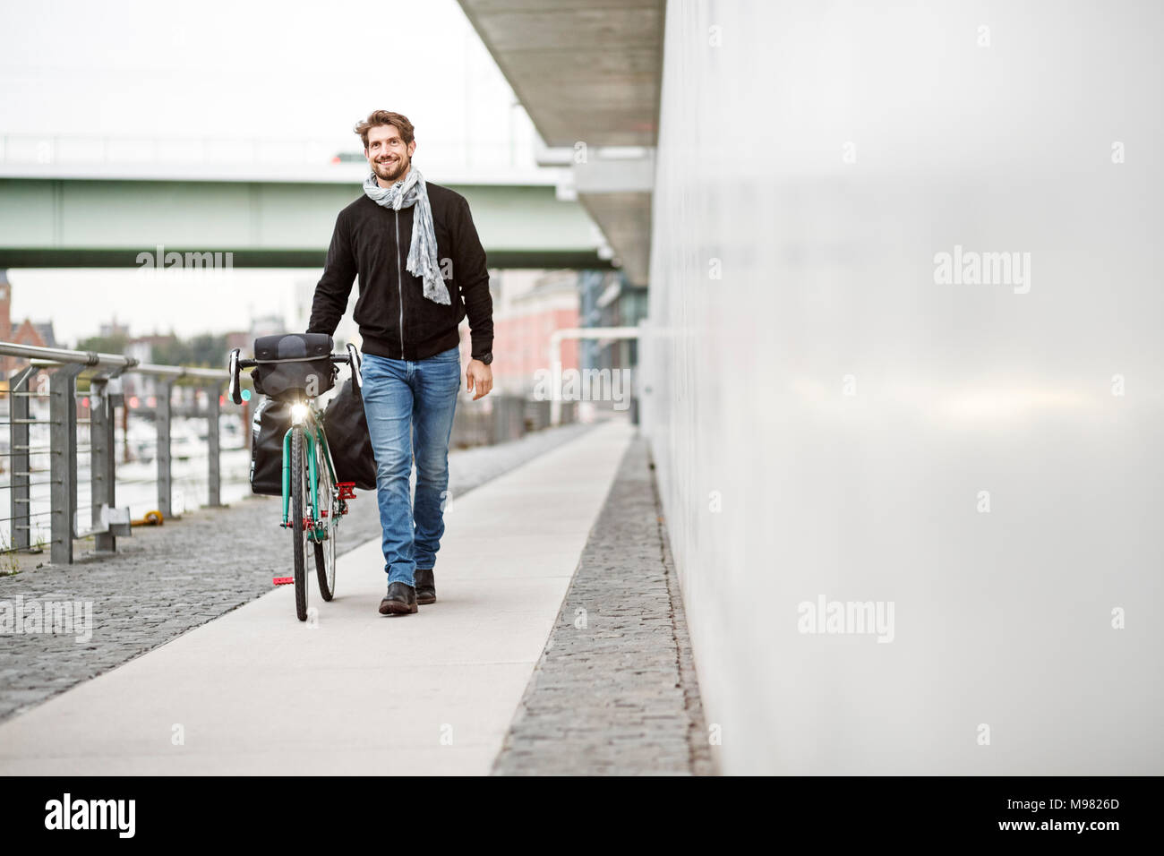 Smiling man pushing bicycle on a path Stock Photo - Alamy