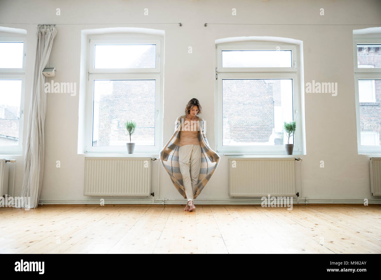Mature woman in empty room standing at the window Stock Photo - Alamy