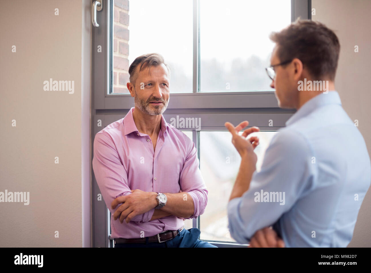 Two businessmen talking at the window Stock Photo - Alamy