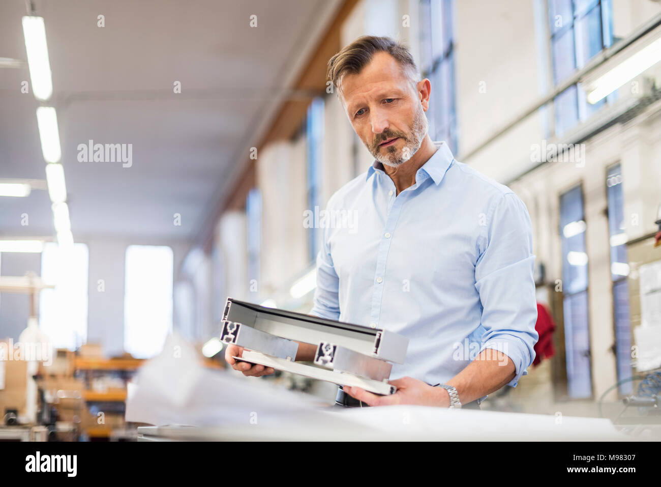 Mature businessman in factory examining component Stock Photo - Alamy