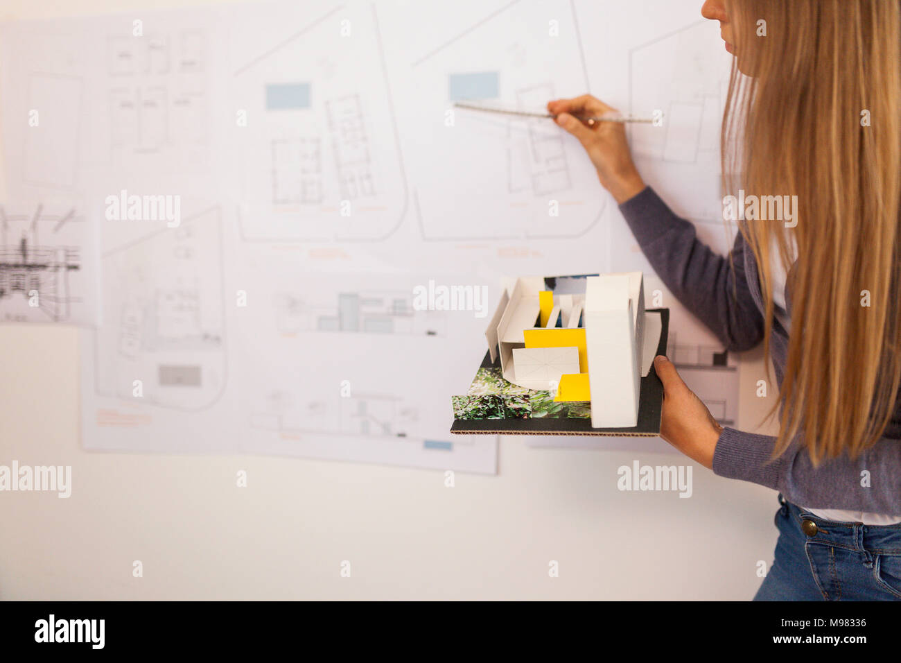 Female architect working on a project, holding architectural model ...