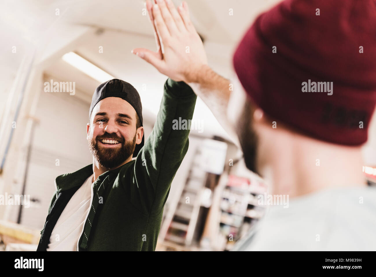 Two happy young men high fiving in workshop Stock Photo - Alamy