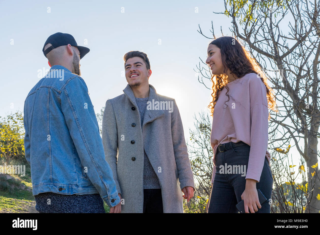 Three smiling friends talking outdoors Stock Photo - Alamy