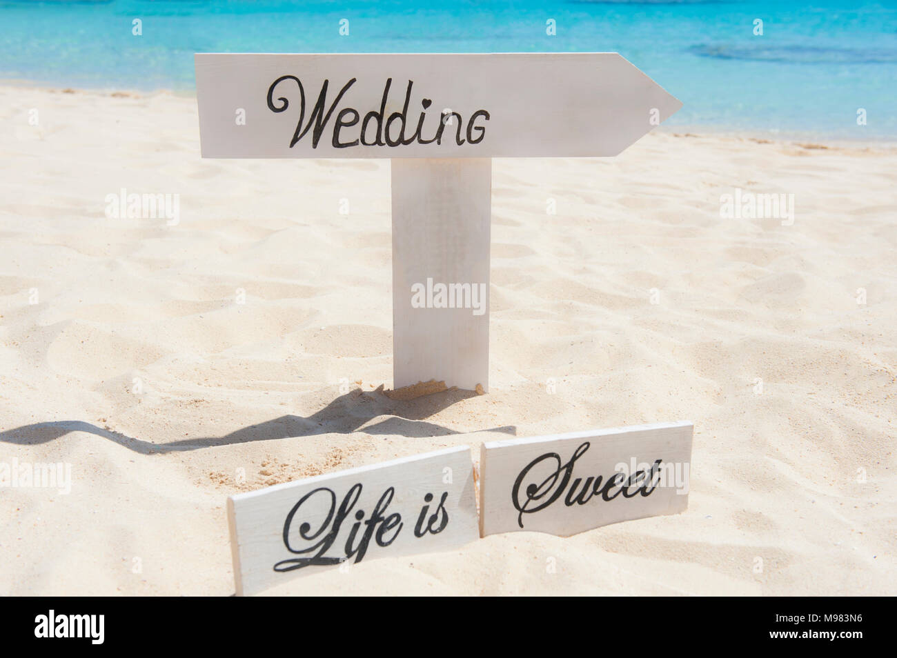 Tropical island beach wedding ceremony setup with signpost and ocean ...