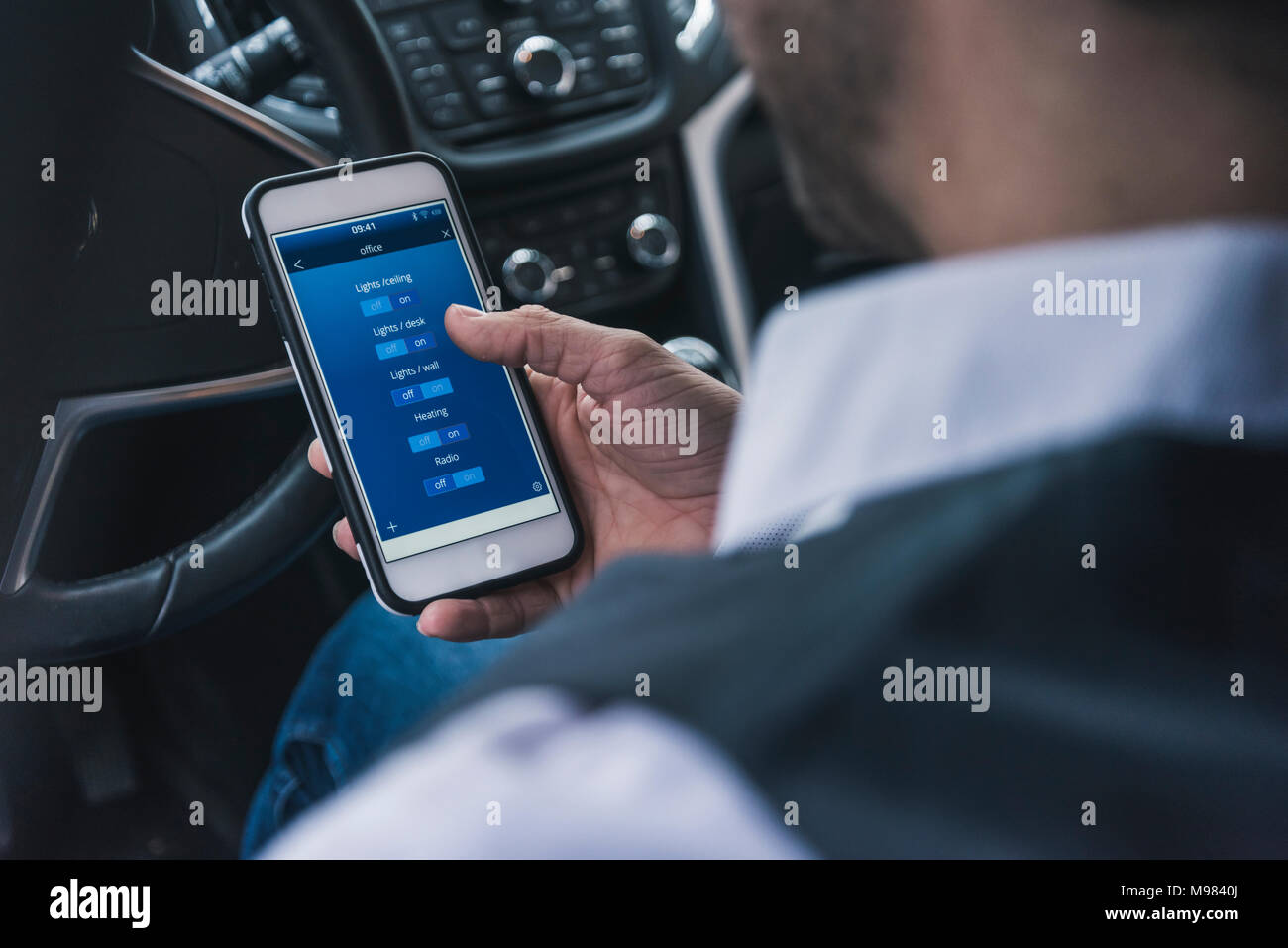 Man in car adjusting smart home devices via smartphone Stock Photo - Alamy