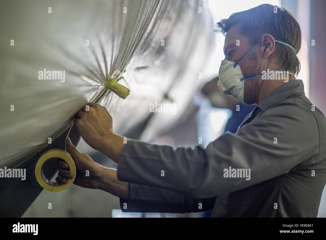 Worker in a factory wearing dust mask taping Stock Photo - Alamy