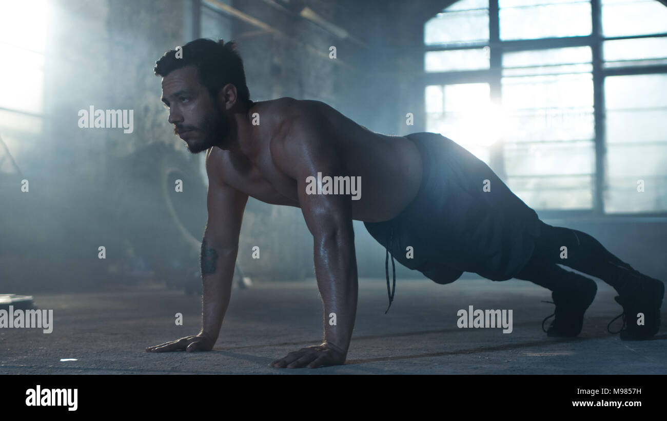 Muscular Shirtless Man Covered in Sweat Does Push-ups in a Deserted ...