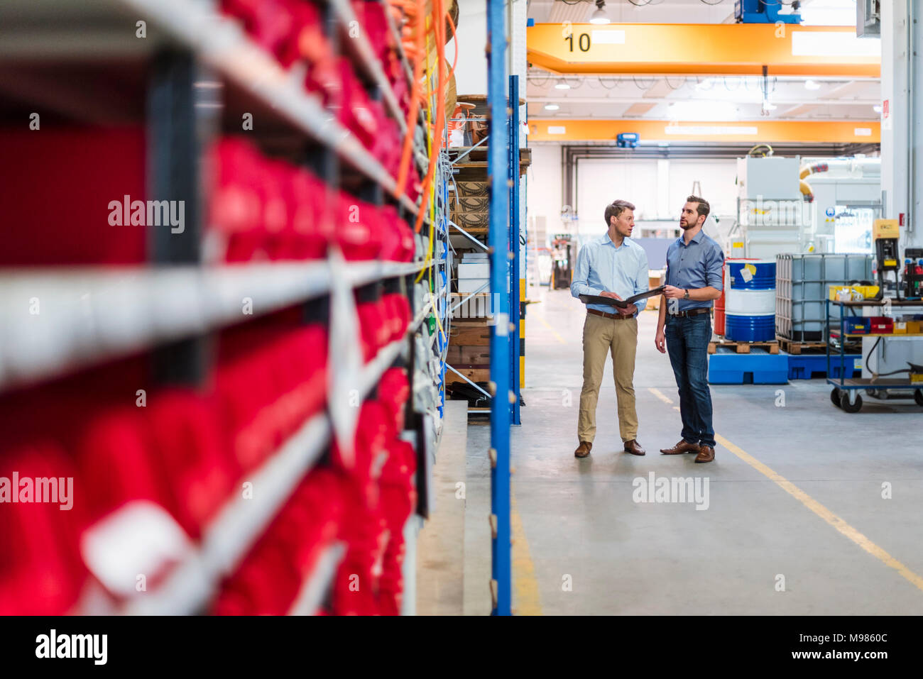 Two men with folder in factory storeroom Stock Photo - Alamy