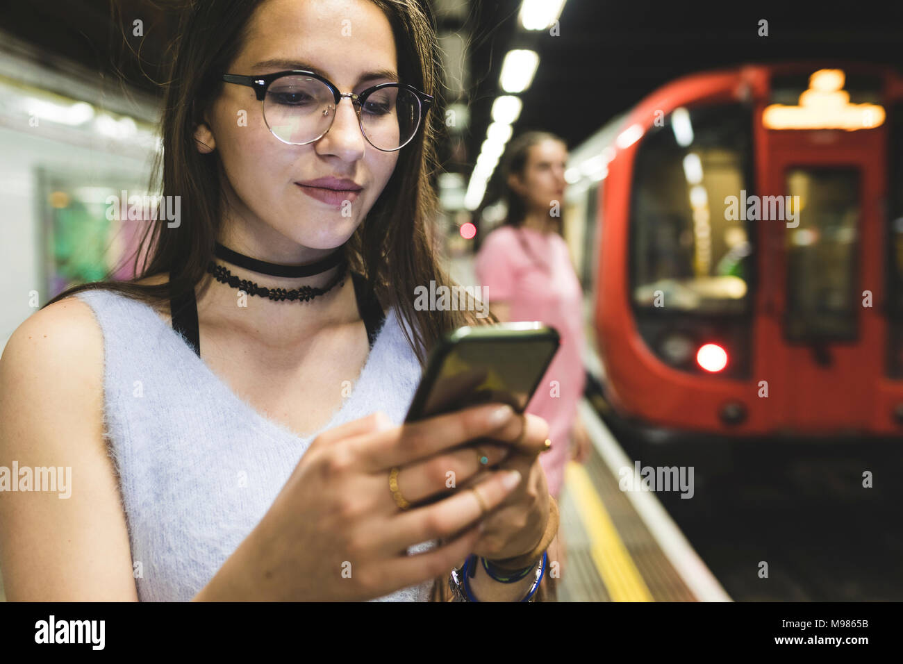 Teenage girl using cell phone at subway station Stock Photo - Alamy