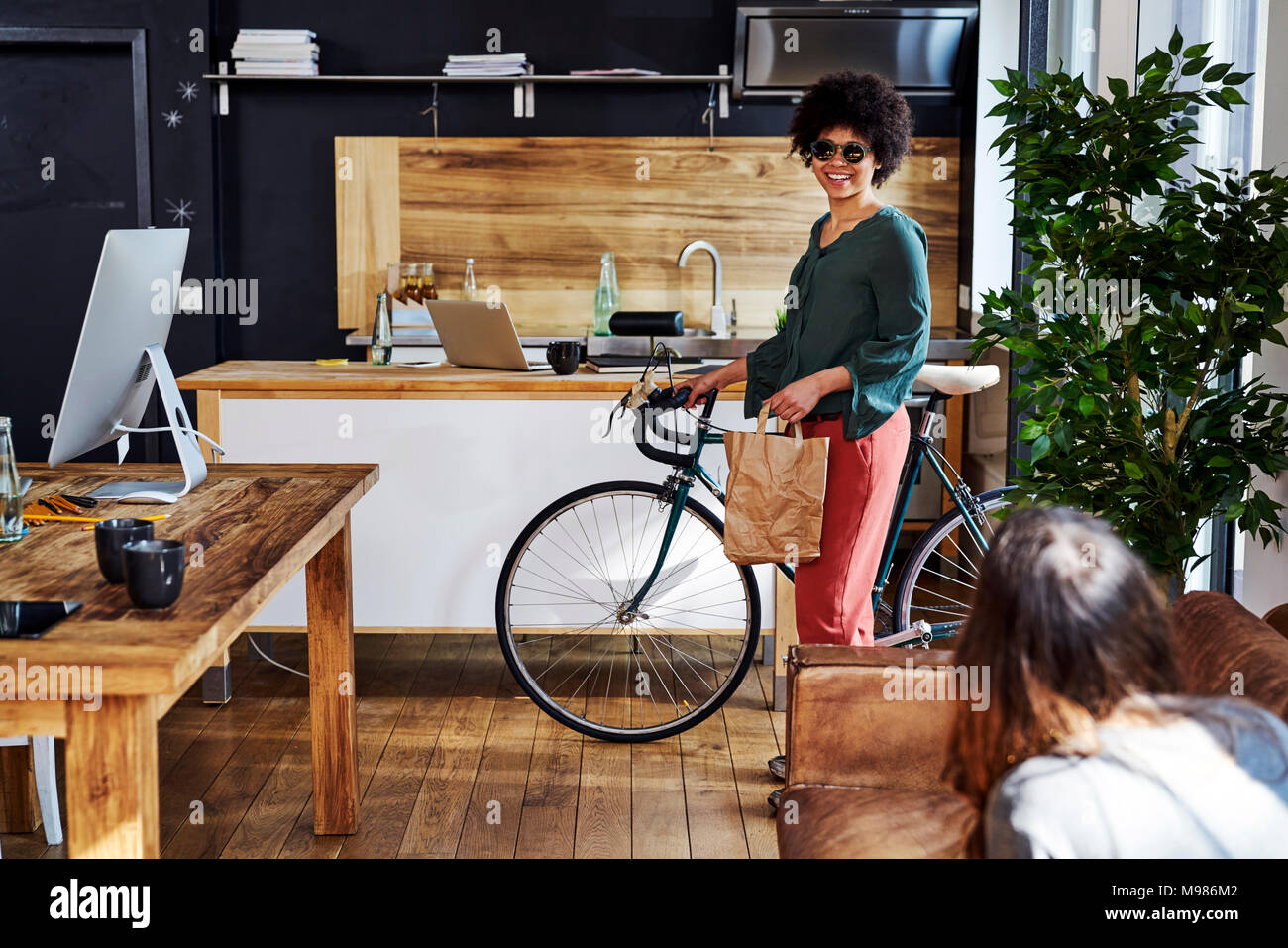 Young woman with bicycle arriving in modern office Stock Photo - Alamy