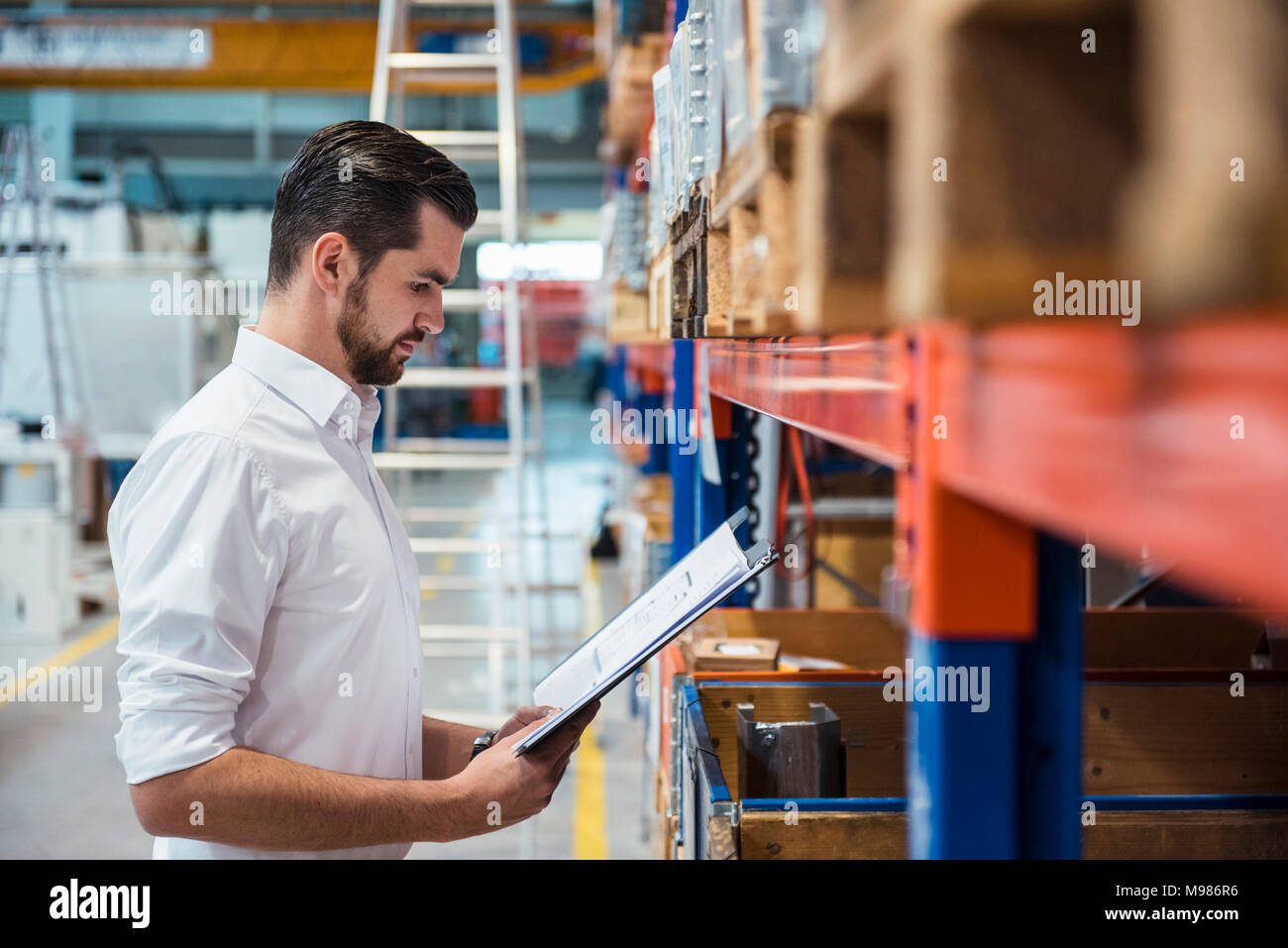 Man in factory storehouse holding folder Stock Photo - Alamy