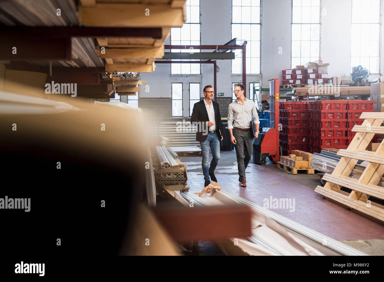 Two businessmen walking in factory storeroom Stock Photo - Alamy