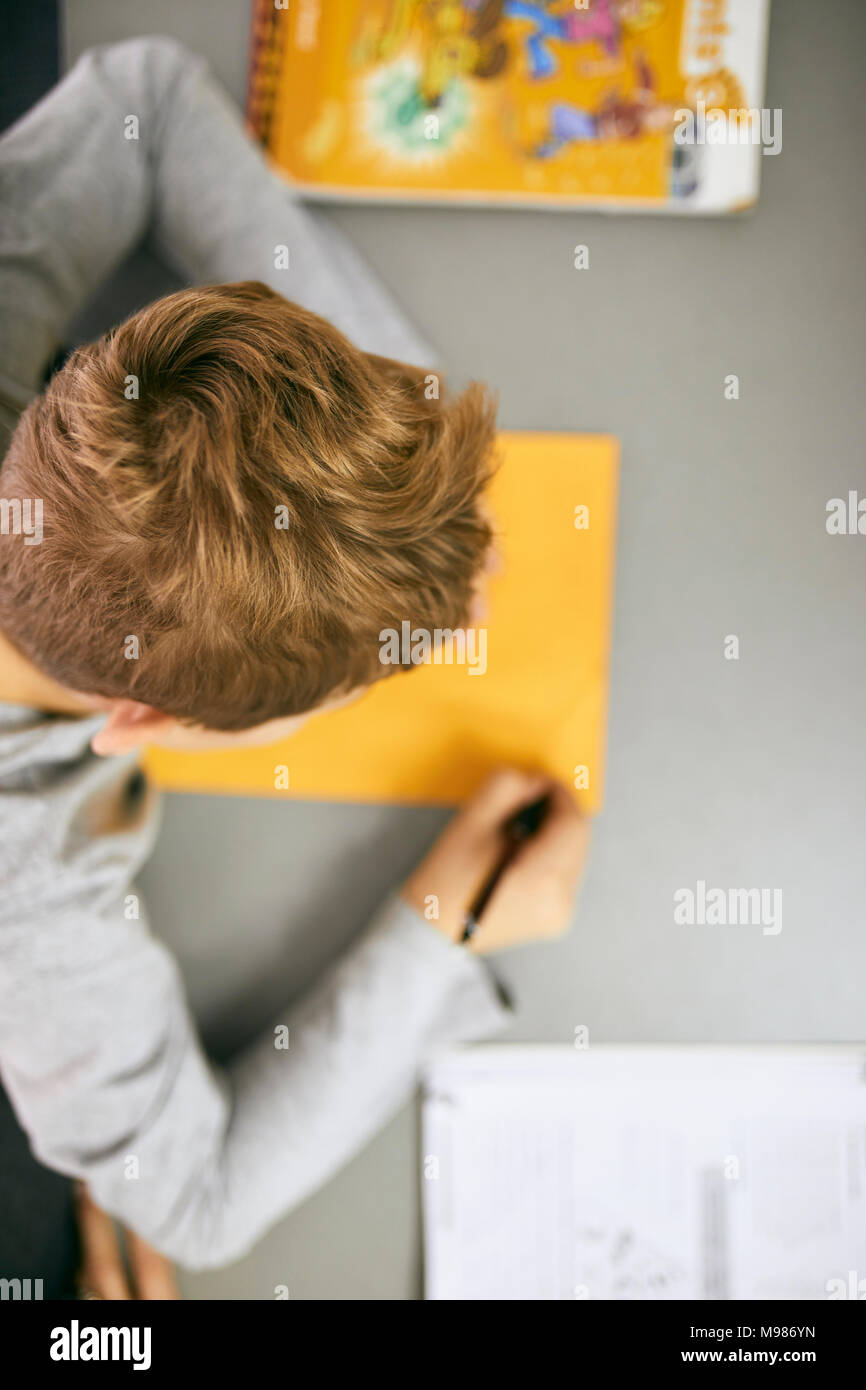 Schoolboy writing on desk in class Stock Photo - Alamy