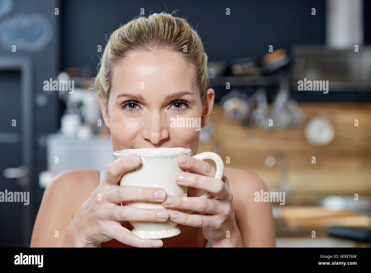 Portrait of smiling blond woman in the kitchen holding coffee mug Stock ...