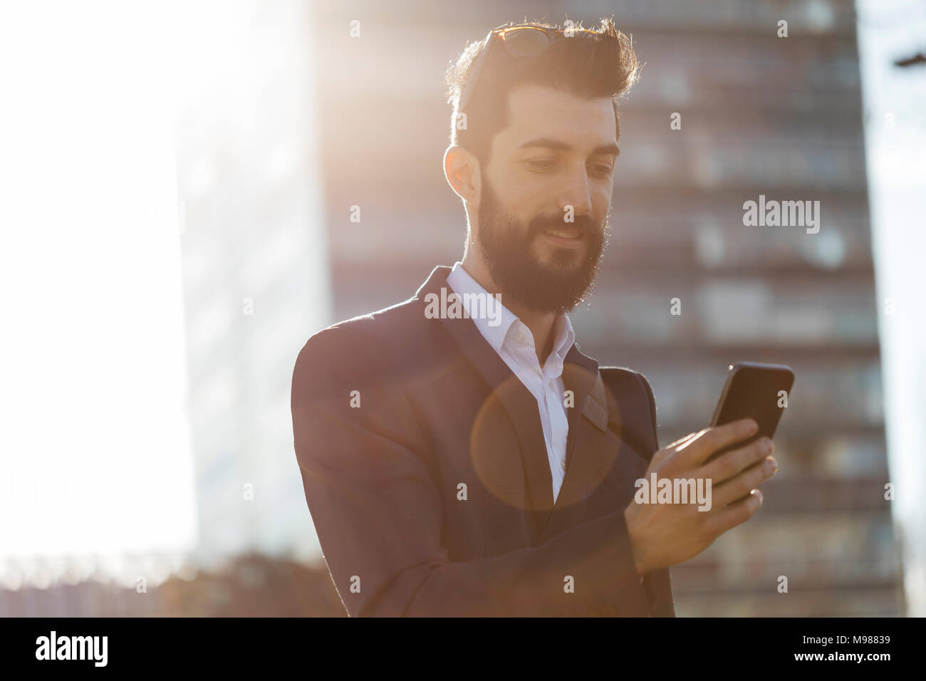 Businessman using cell phone outside office building Stock Photo - Alamy