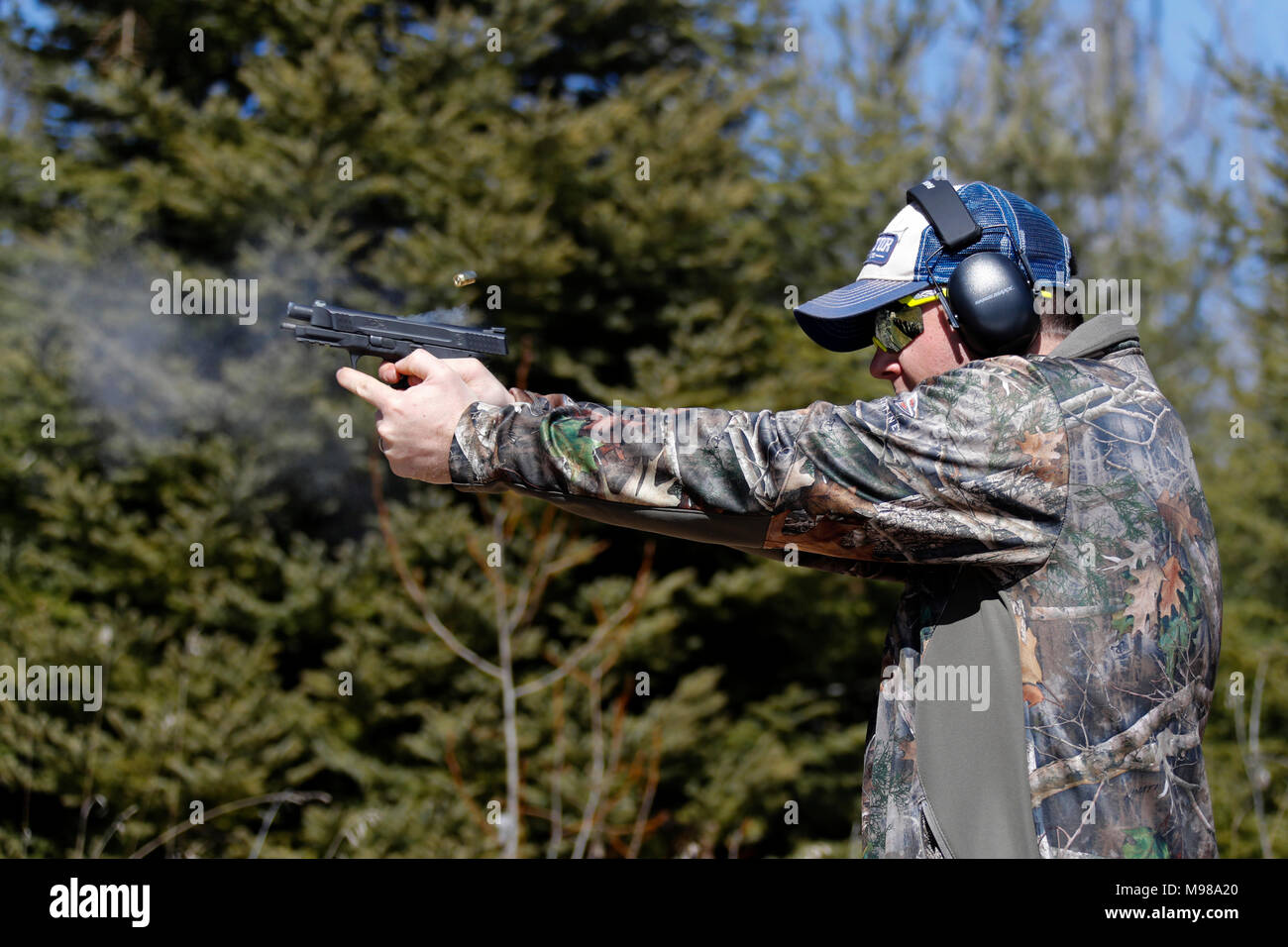 A man shooting a handgun and the ejected shell is visible in the air ...
