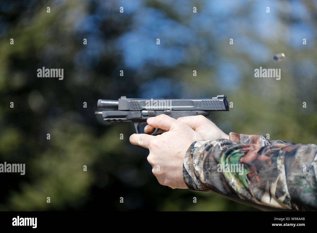 Close-up of a pistol in full recoil and the ejected shell is in the air ...