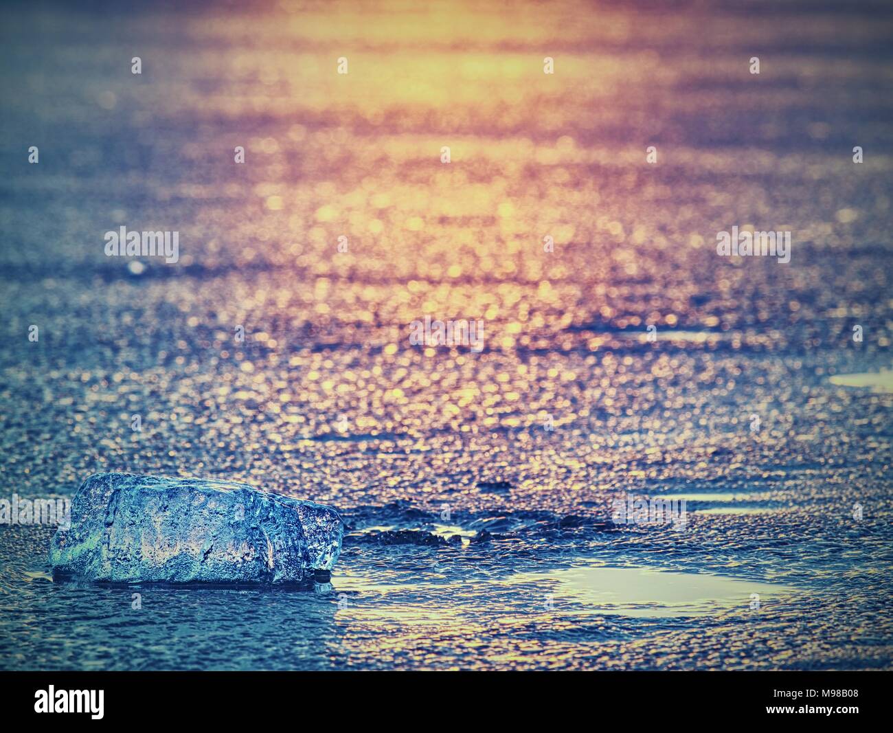 Shiny cold ice, bright icicles on frozen lake shore. Warm sun rays of ...