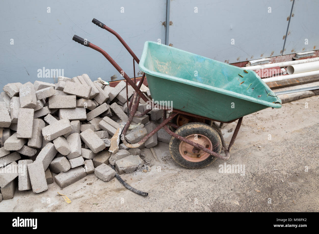 Stacked bricks with wheelbarrow in construction site Stock Photo - Alamy