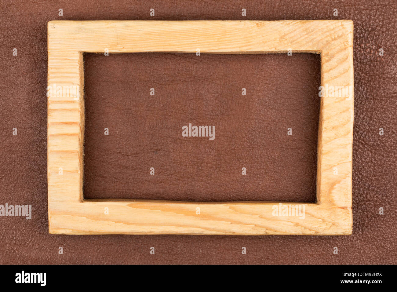 Rectangular frame made from light wood lies on brown natural leather ...