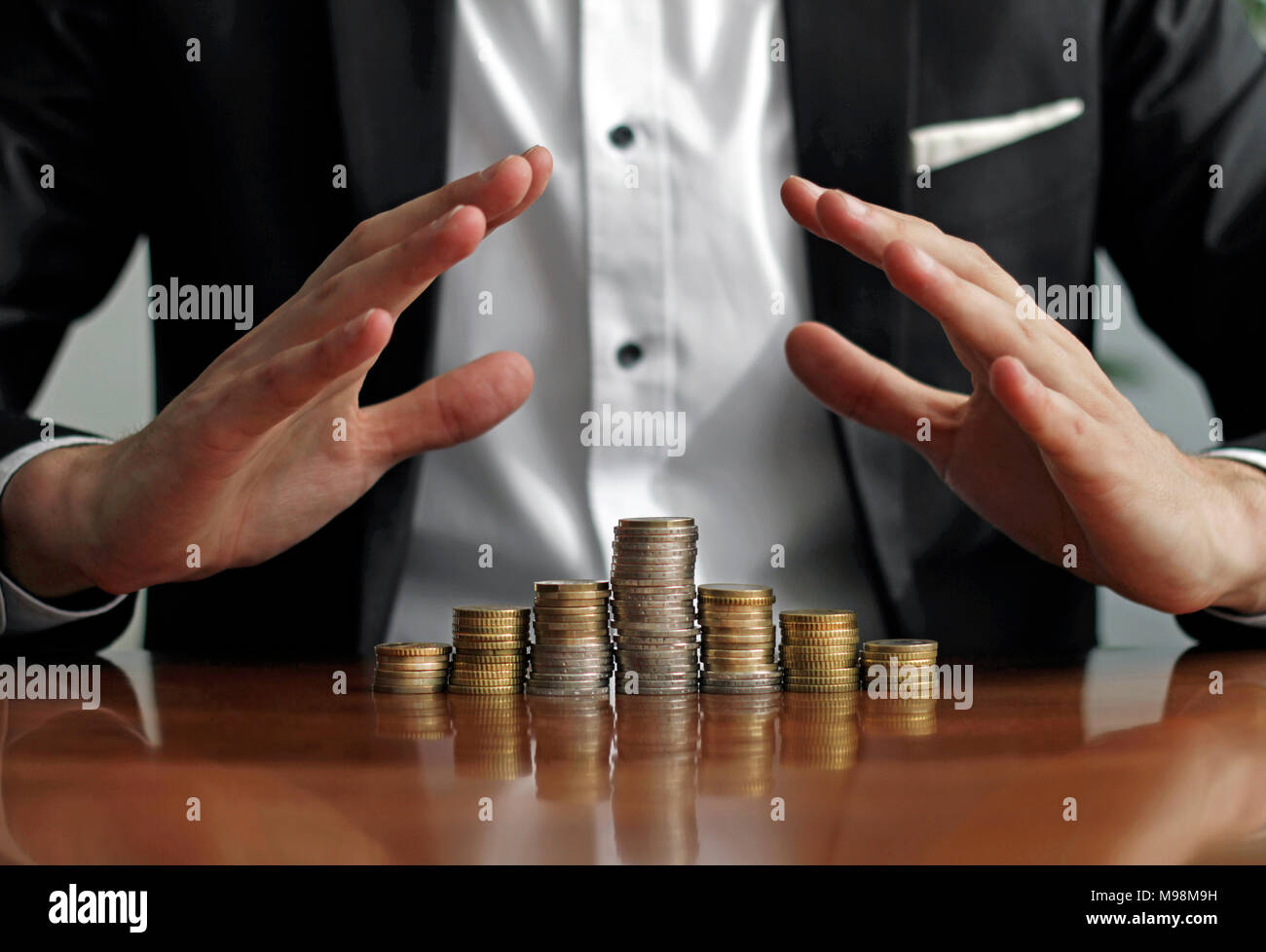 Man protecting money with hands Stock Photo - Alamy