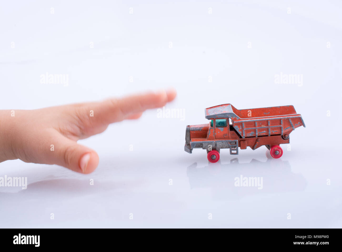 Baby hand is about to grab a red toy truck on white background Stock ...