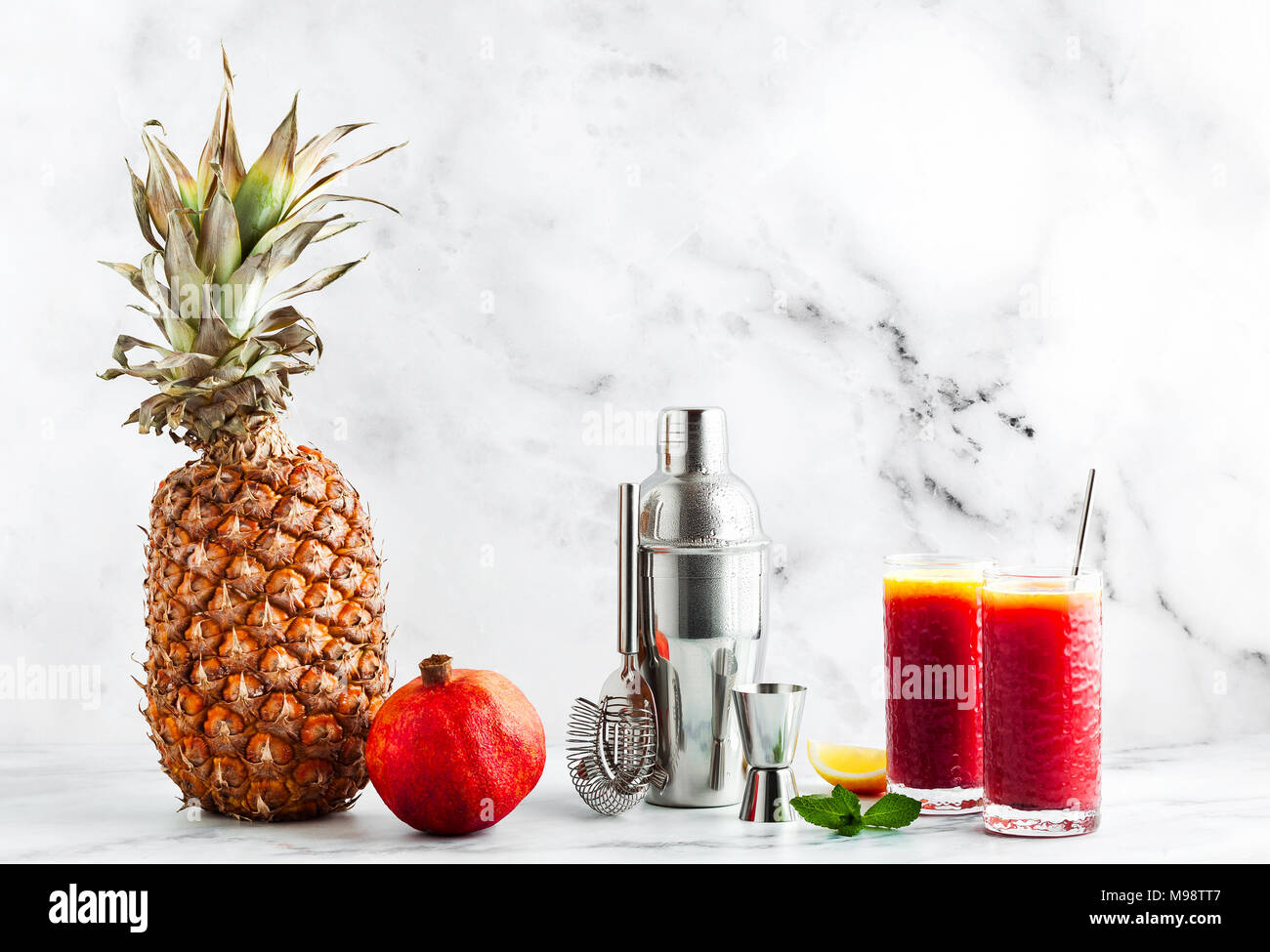 mixing tequila sunrise in a shaker on a marble table from pineapple and ...