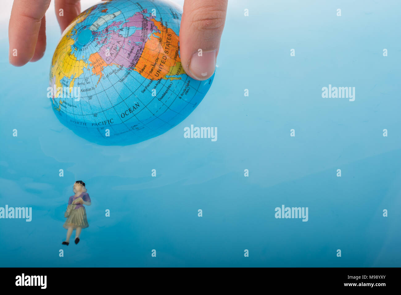 Little globe with floating figurines around in water Stock Photo - Alamy